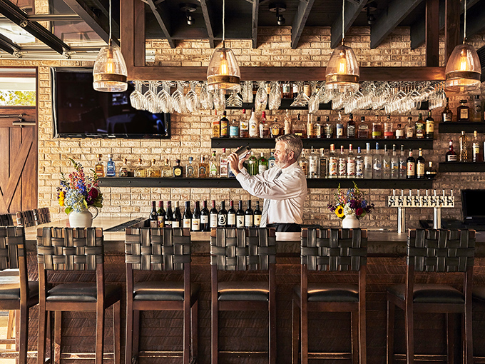 Behind every great bar is a professional who treats bottle arrangement like a form of meditation. The hanging glassware creates a crystal chandelier effect.