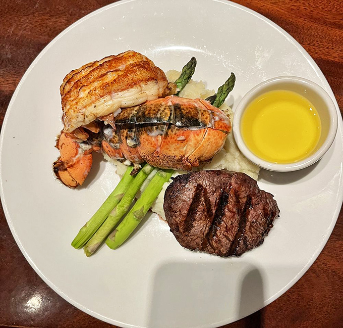The ultimate power couple: lobster tail and filet mignon sharing a plate like they were made for each other, with asparagus playing matchmaker.