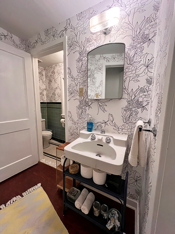The bathroom features whimsical floral wallpaper and modern fixtures. Even practical spaces maintain the storybook charm that makes this place special.