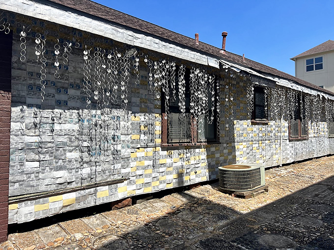 The side view reveals the full spectacle of the aluminum siding, where thousands of cans create a rippling, metallic effect in the Texas sun.