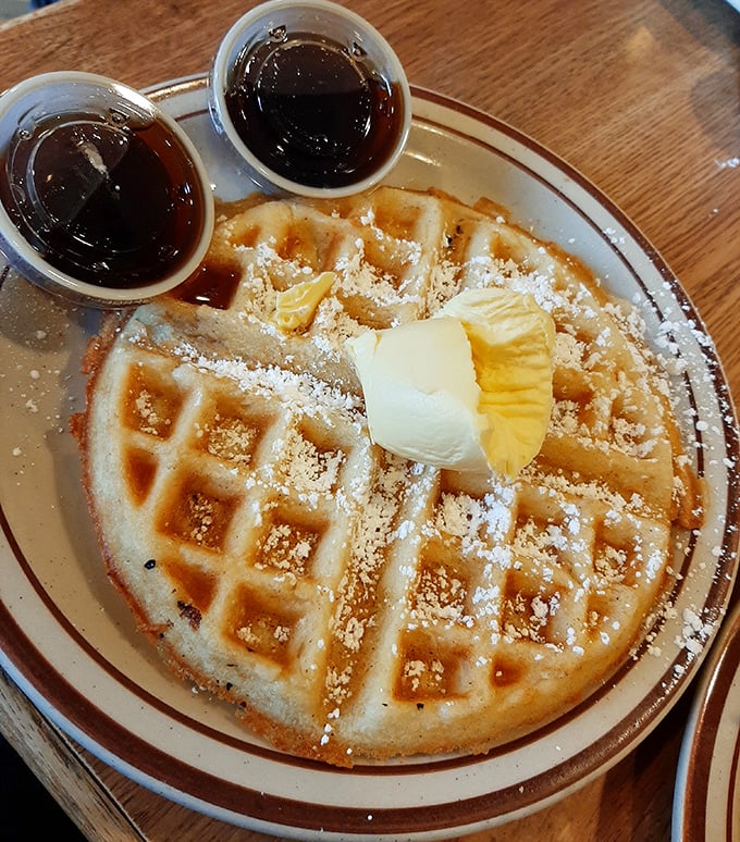This Belgian waffle isn't just breakfast&mdash;it's an edible pedestal for butter, powdered sugar, and syrup. The twin cups of syrup stand ready, like backup dancers waiting for their cue.