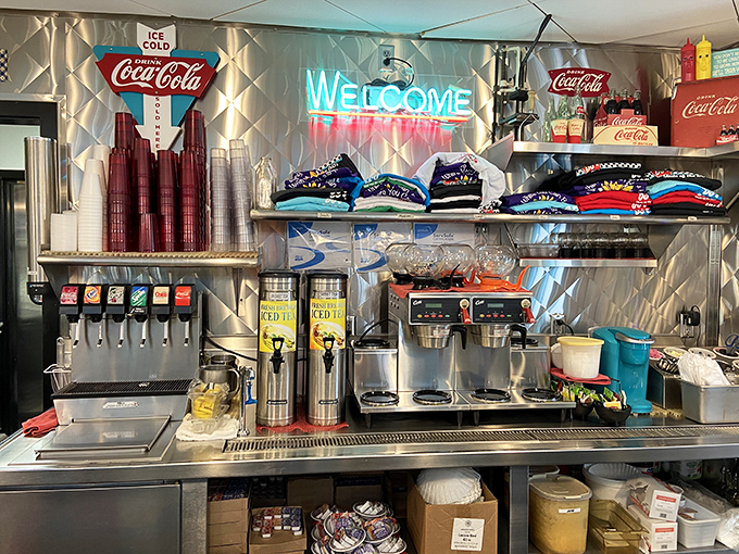 The beverage station gleams with promise, while neon "Welcome" signs remind you that hospitality never needed a software update.