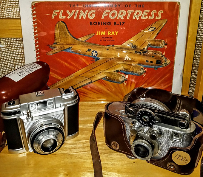 Vintage cameras that captured moments long before selfies existed, displayed alongside a Flying Fortress book that takes you back to WWII.