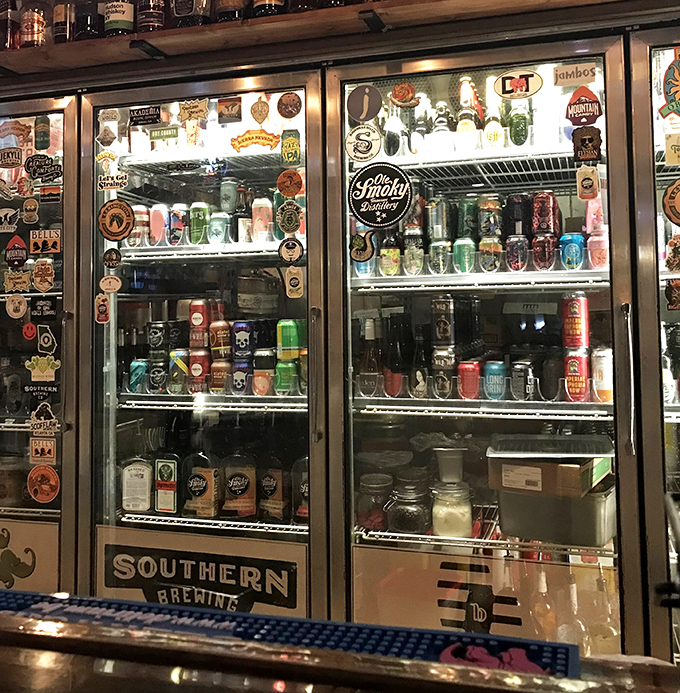 The beer fridge stands like a shrine to hoppy goodness. Each can and bottle waits patiently for its moment to complement your burger masterpiece.