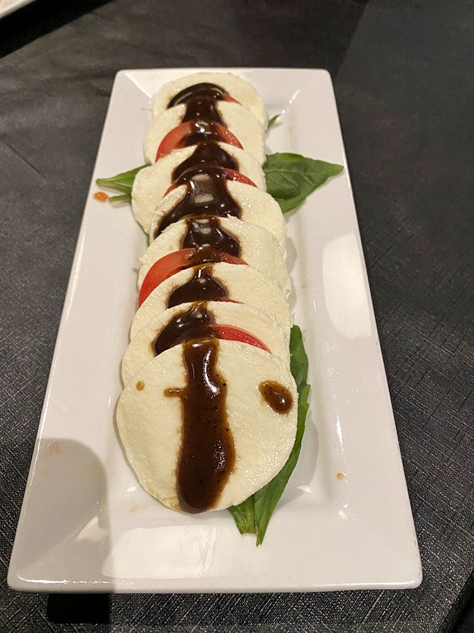 The Caprese salad lines up like synchronized swimmers of mozzarella and tomato in a balsamic pool.