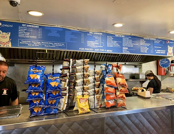 Chips stand at attention like soldiers awaiting deployment alongside their sandwich commanders. The menu board serves as their battle plan.