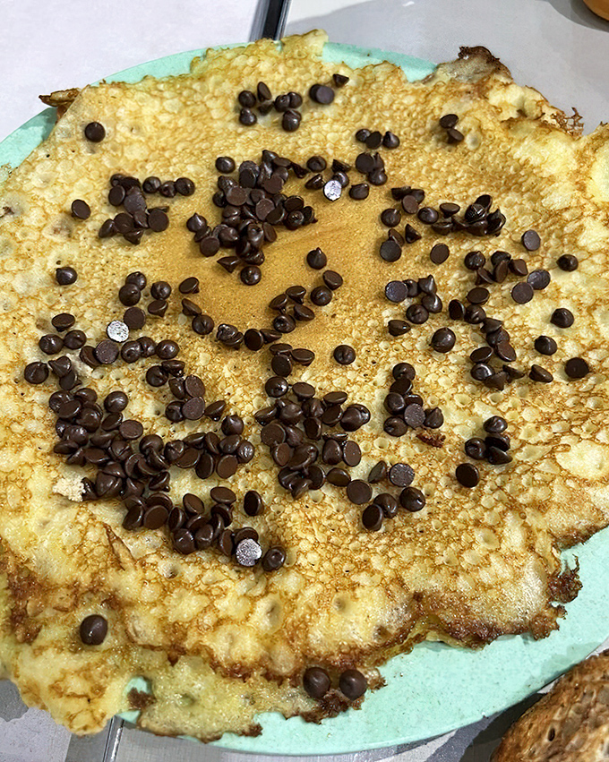 A hotcake with chocolate chips arranged in a smiley face &ndash; because breakfast should start with a wink and a nod.