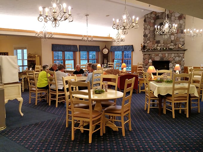 Chandeliers meet rustic charm in this dining area, where the stone fireplace has witnessed more family celebrations than a lifetime of birthday cakes.