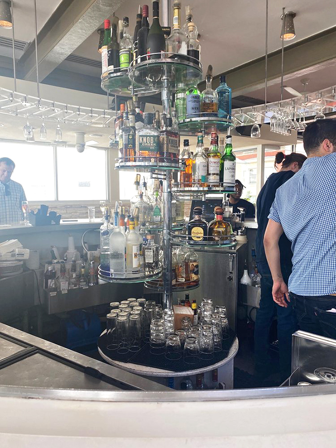 The bar's impressive liquor display doubles as functional art, with bottles arranged in a circular tower that bartenders navigate with practiced precision.
