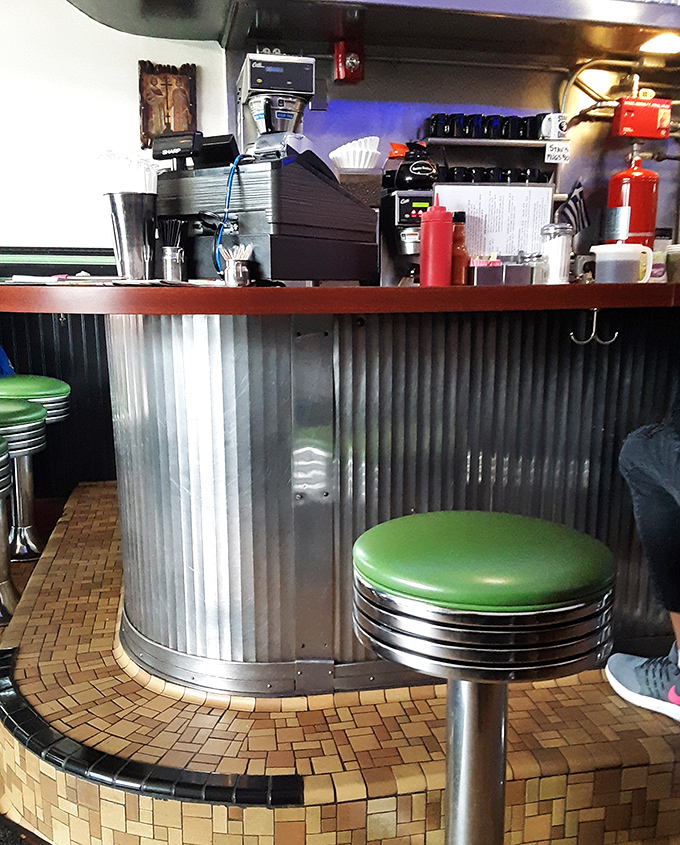 That corrugated metal counter with mint green stools&mdash;the breakfast bar where strangers become neighbors over coffee refills and shared weather complaints.