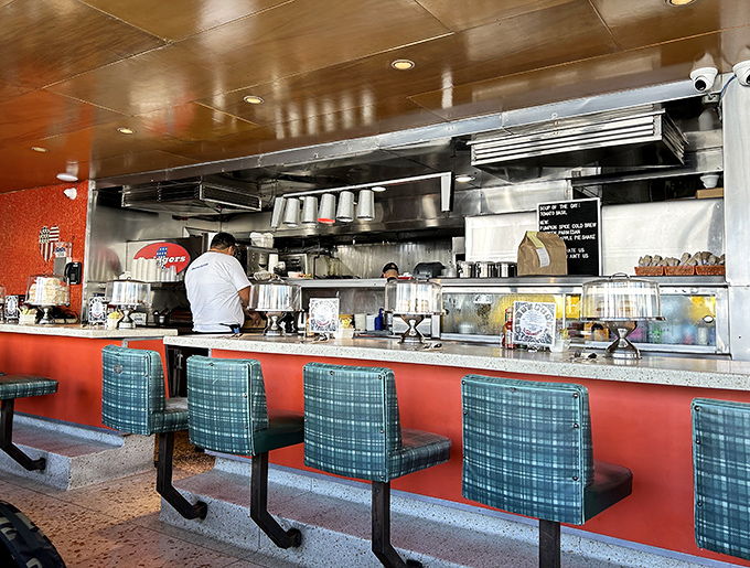 The counter where strangers become temporary neighbors, united by the universal language of "pass the hot sauce, please."