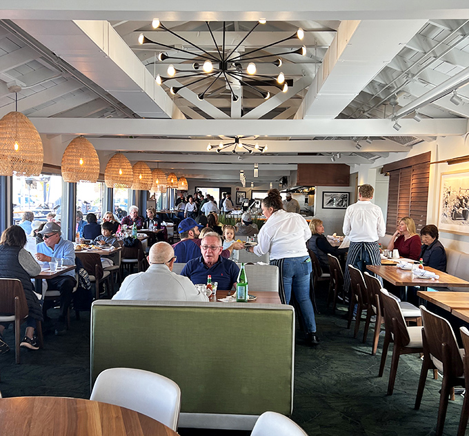 A bustling dining room where conversations flow as freely as the wine, under distinctive basket pendant lights.