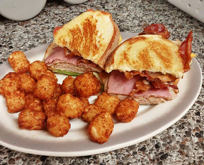 This club sandwich isn't playing around—layered higher than my winter clothing in Michigan January, with tater tots that crunch louder than autumn leaves.