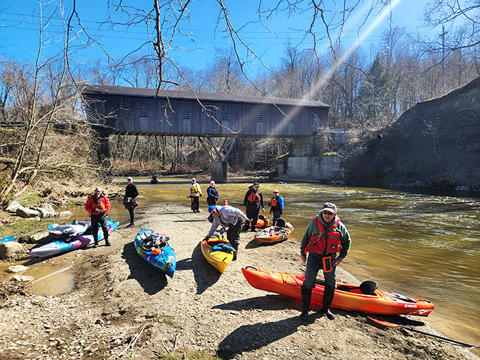 Adventure awaits beneath historic timbers, where colorful kayaks and brave paddlers prepare to navigate Conneaut's scenic waterways.