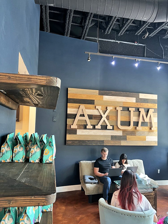 The cozy seating area where laptops meet lattes and the wooden AXUM sign watches over productive procrastination.
