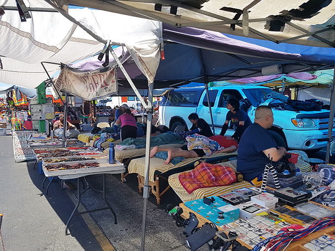 A patchwork of tarps shelters vendors selling everything from bedding to electronics—urban merchandising at its most resourceful and diverse.