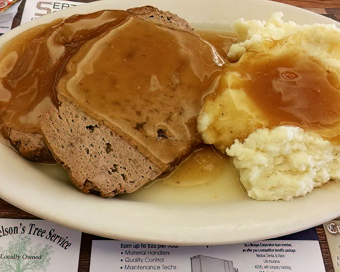Meatloaf and mashed potatoes swimming in gravy lake—comfort food that doesn't just hug you, it writes you into its will.