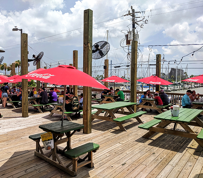 Outdoor dining at Tookie's: where Gulf breezes, red umbrellas, and the distant sound of boats create the perfect backdrop for seafood feasting.