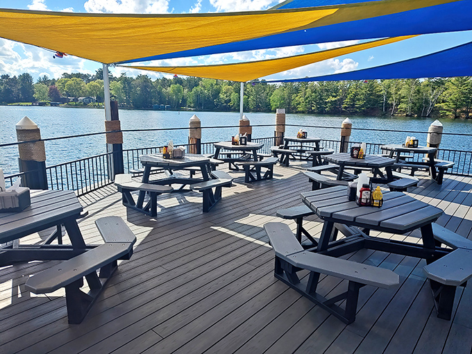 Outdoor dining under blue and yellow canopies creates the perfect lakeside escape &ndash; where picnic tables and water views elevate every bite to vacation status.