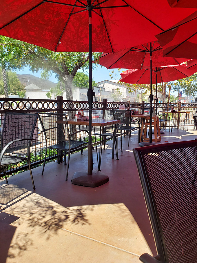 Dappled sunshine filters through red umbrellas on the patio, creating the perfect outdoor setting for enjoying smoky treasures while watching Old Town stroll by.