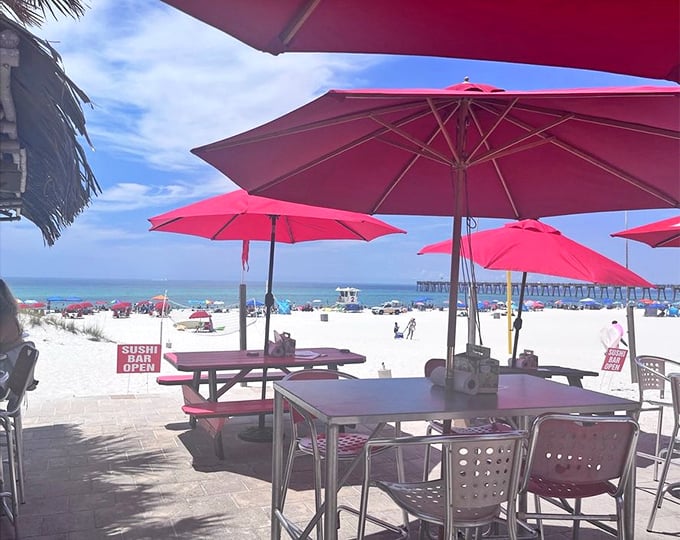 Pink umbrellas frame a view that belongs on your screensaver&mdash;powdery white sand meeting emerald waters while you contemplate another round.