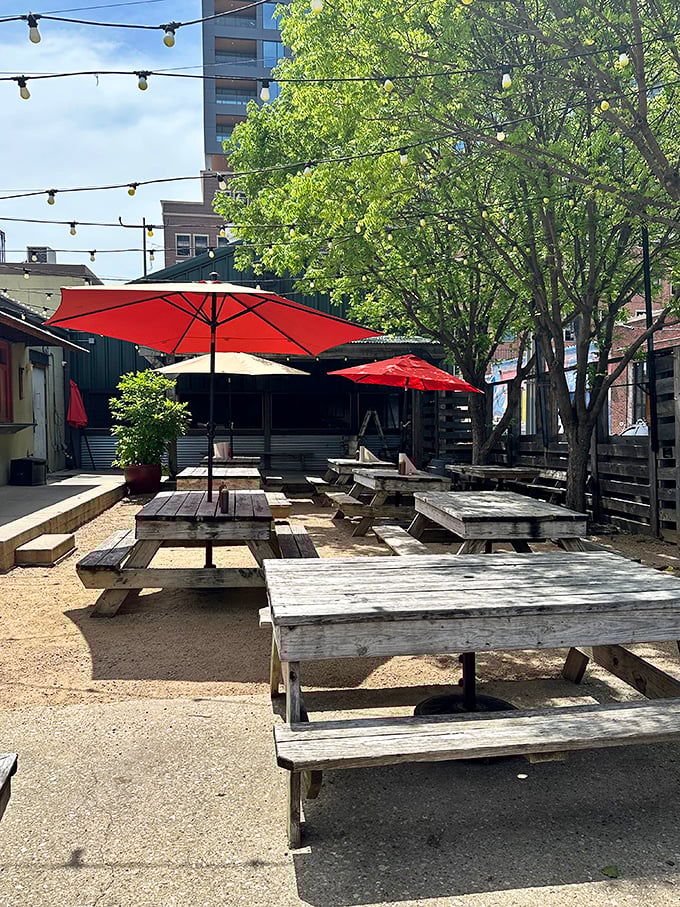 The outdoor picnic area offers a rustic respite where string lights, shade trees, and red umbrellas create the perfect Texas al fresco experience.