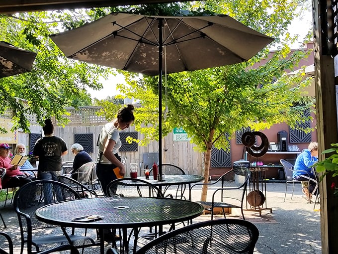 The patio offers dappled shade and fresh air, where summer afternoons stretch lazily into evening under market umbrellas.