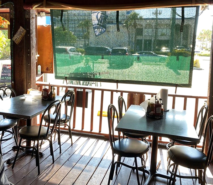 The screened porch&mdash;where indoor comfort meets outdoor vibes. These wooden tables have hosted more memorable conversations than most therapists' offices.