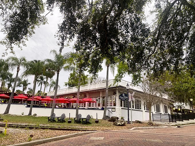 Pisces Rising's outdoor dining area, where red umbrellas and palm trees create the perfect Florida dining backdrop.