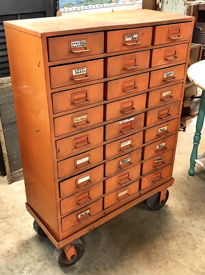 This rolling parts cabinet has more drawers than a Southern gossip has stories, each one labeled with mechanical mysteries waiting to be solved.