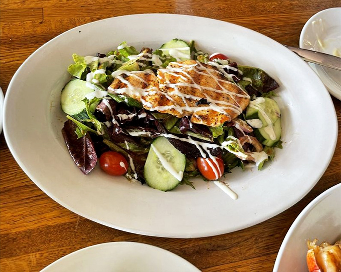 Grilled salmon crowning fresh greens, creating a salad that actually satisfies like a proper meal should. 