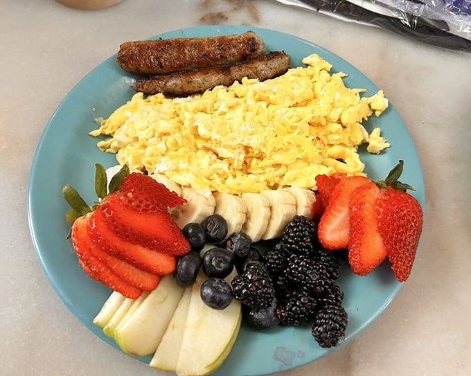 Breakfast's holy trinity: perfectly scrambled eggs, sausage, and a fruit medley that makes eating healthy feel like cheating.
