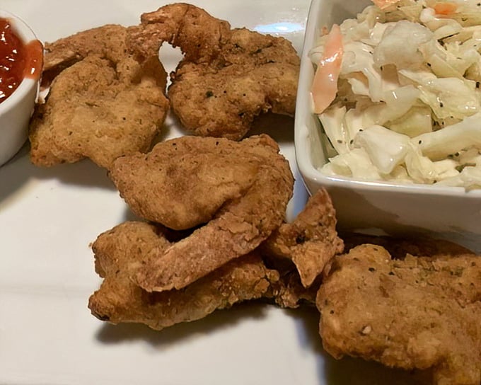 Golden-fried chicken tenders with creamy coleslaw&mdash;proof that sometimes the simplest dishes, executed perfectly, can outshine the fanciest culinary creations.