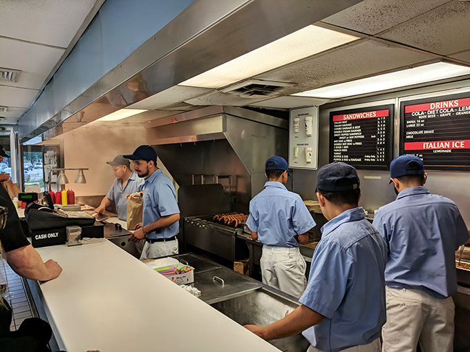 The blue-shirted beef brigade works with the precision of NASA engineers, transforming simple ingredients into sandwiches worthy of worship.