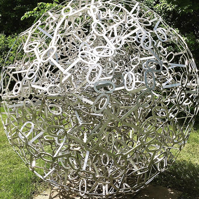 A metallic sphere of letters and numbers creates a galaxy of communication, words frozen in a cosmic dance.