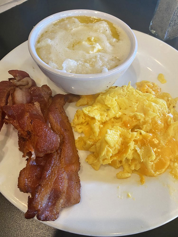 Breakfast fundamentals executed with precision: scrambled eggs that cloud-like, bacon with the perfect crisp-to-chew ratio, and grits that would make a Southerner nod approvingly.