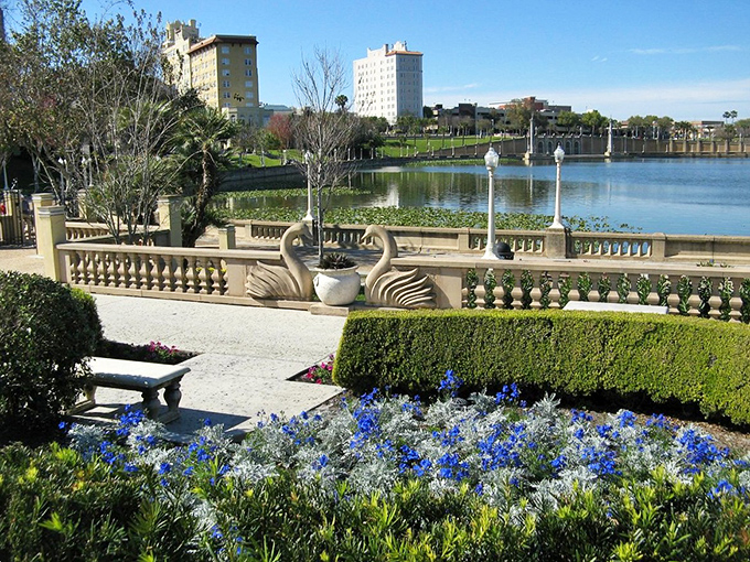 Swan sculptures guard Lake Mirror like elegant sentinels, while flowers bloom in a palette that would make Monet reach for his brushes.