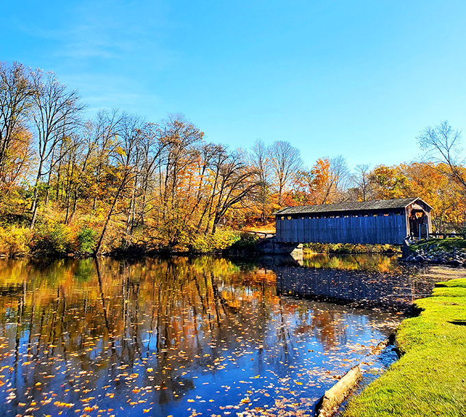Autumn transforms Fallasburg into a painter's palette of reds and golds, the bridge standing as a steadfast gray anchor amid nature's seasonal show.