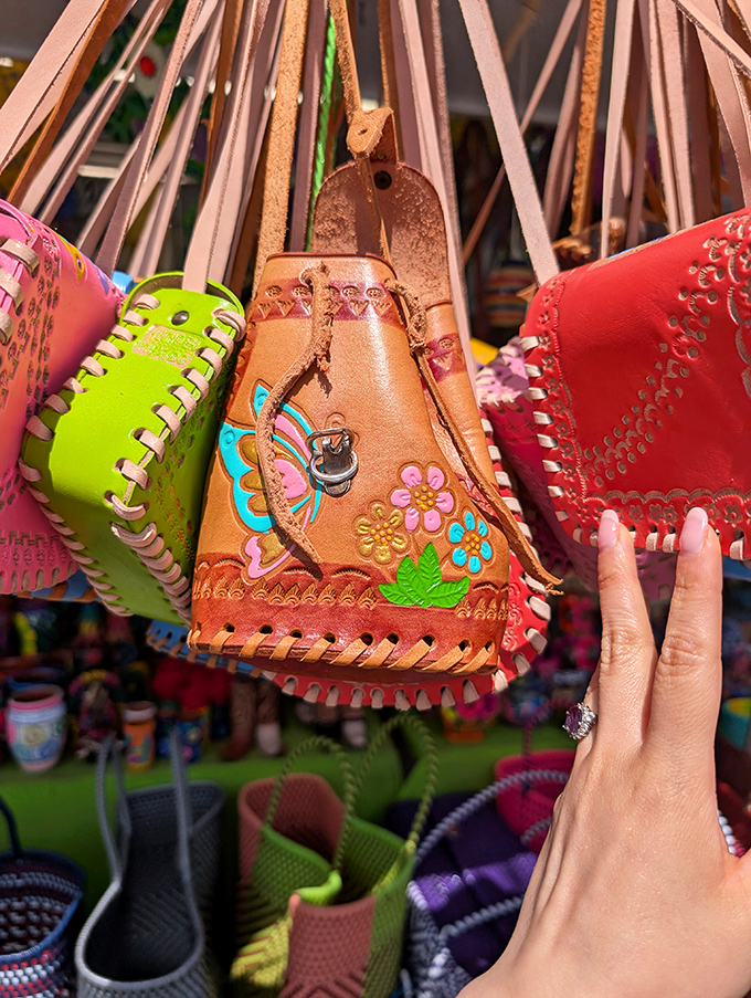 Handcrafted leather purses swing like colorful pendulums, each one telling a different story through intricate designs and vibrant hues.