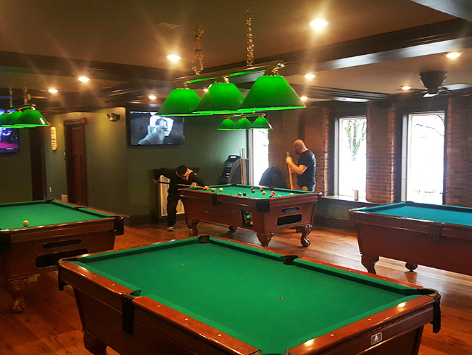 Multiple pool tables under emerald lighting create the perfect setting for friendly competition and post-dinner entertainment sessions.