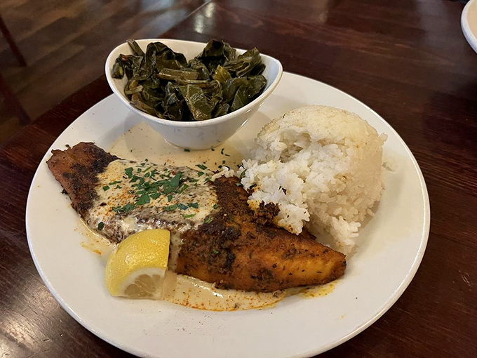 Blackened catfish that's wearing its seasoning like a badge of honor. Those collard greens and rice aren't sidekicks&mdash;they're essential companions on this flavor journey.