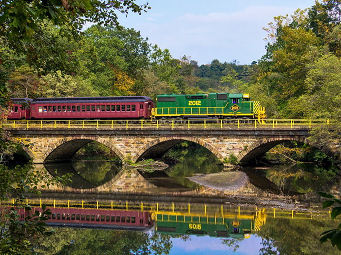 This stone arch bridge doesn't just span water&mdash;it connects centuries, carrying colorful train cars over reflections that double the visual feast.