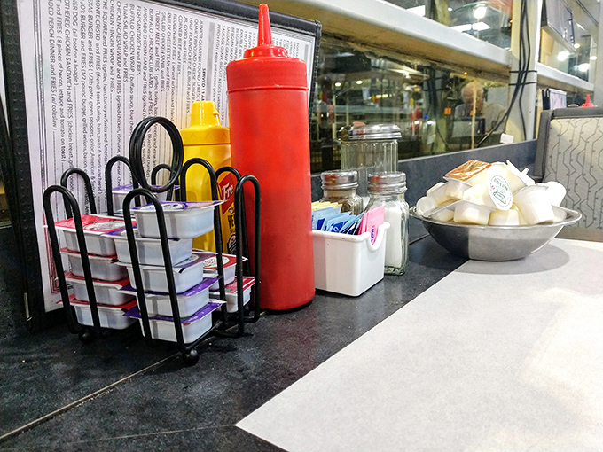 The condiment caddy – civilization's greatest achievement. Sugar packets, jellies, and ketchup – the holy trinity of diner enhancement.