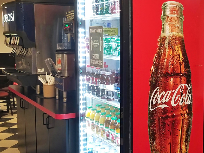 The drink cooler glows like a beacon of refreshment, standing guard beside a Coca-Cola bottle that's practically architectural.