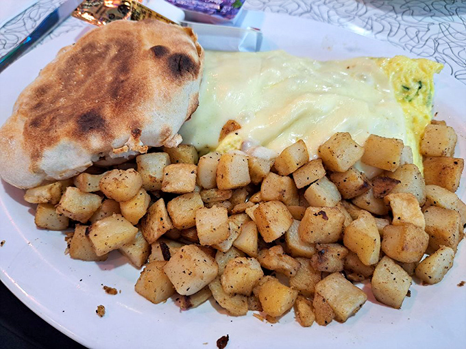 Breakfast architecture at its finest. Perfectly seasoned home fries, English muffin, and an omelet draped in melted cheese&mdash;pure morning magic.