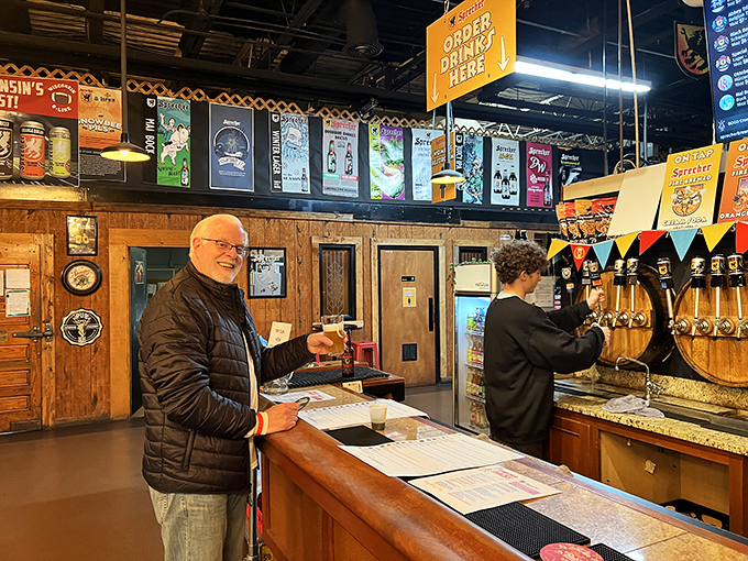 The taproom bar, where dreams come true one pour at a time. That smile says he's about to experience something transformative.