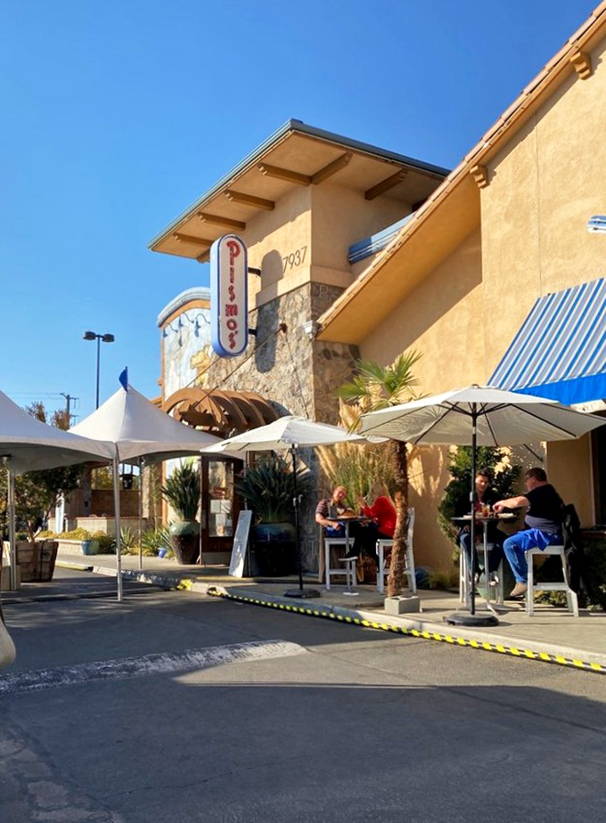 Outdoor tables under white umbrellas create impromptu coastal dining, even in Fresno's heat. The palm-fringed fa&ccedil;ade completes the coastal illusion.