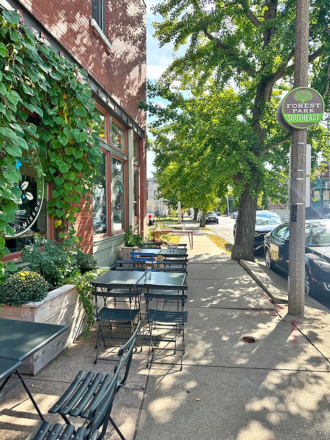 Dappled sunlight filters through trees onto sidewalk seating, offering a tranquil urban oasis for your morning meal.