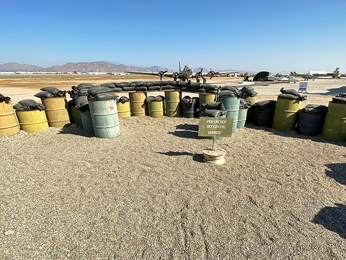 A sobering recreation of perimeter defenses shows how airfields themselves became targets, with oil drums and sandbags forming improvised protection.