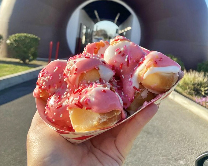 Bite-sized pink perfection held against their birthplace. These donut holes, dressed in strawberry glaze and sprinkles, prove good things really do come in small packages.
